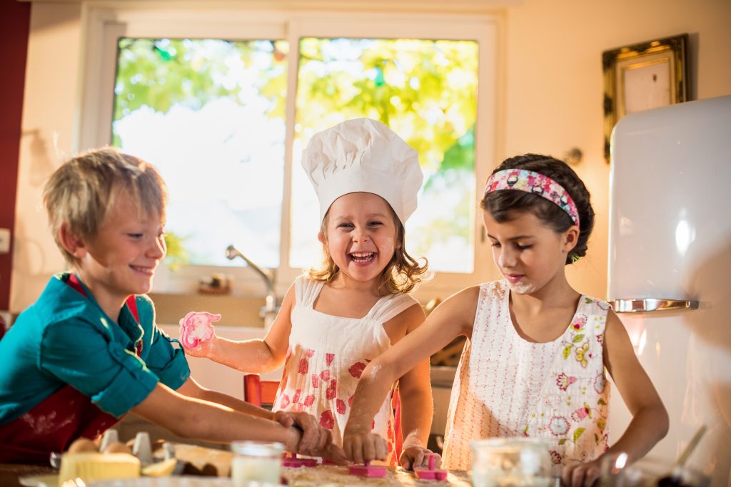 Three brother and sisters are cooking together in the kitchen ...
